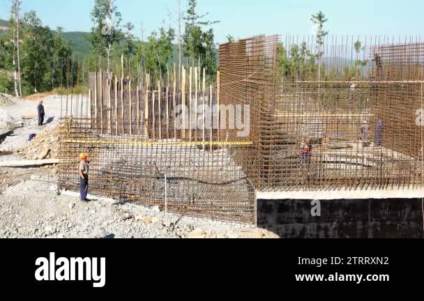 Builders in helmets reinforce the mesh and put the formwork before ...
