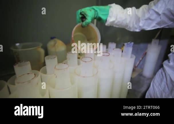 Rows of plastic water filters are being filled in with white liquid by ...