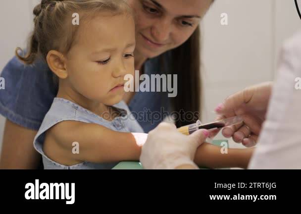 Little girl with mother in hospital. Nurse taking girls venous blood ...