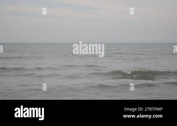 The waves of the Caspian Sea are rolled on a sandy and shell beach with ...