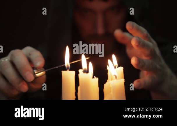 man doing the magic ritual. close-up several candle and old book ...
