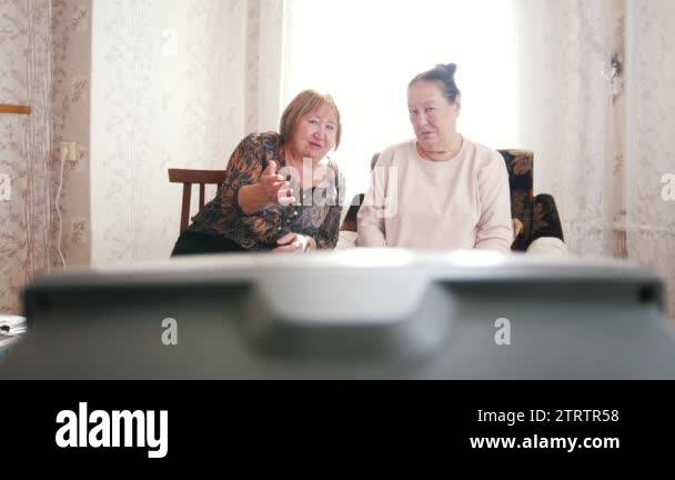 Two old women watching TV and talking to each other Stock Video Footage ...