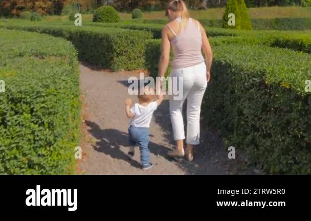 Adorable 1 year old baby boy walking with mother at garden labyrinth ...