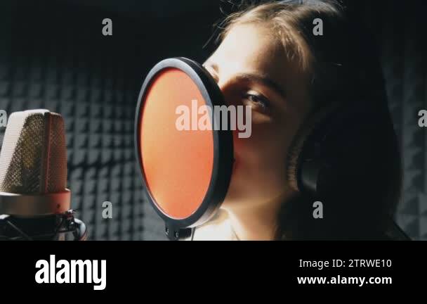 Beautiful girl singing in sound studio. Young singer emotionally ...