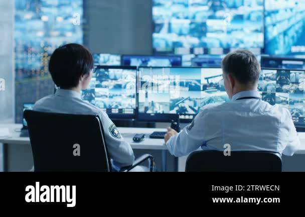 In the Security Control Room Two Officers Monitoring Multiple Screens ...