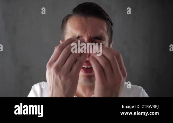 Young man in despair crying covering his face with his hand ...