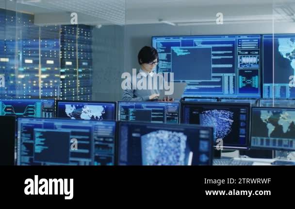 In the System Control Room IT Technician Holds and Works on a Laptop ...