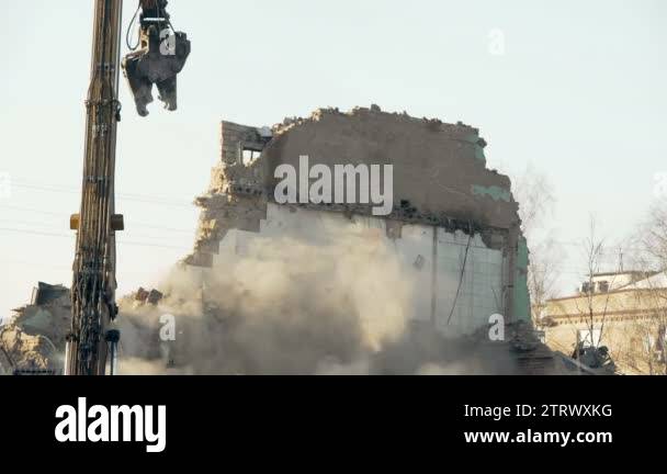 Demolition tool pulling down high wall, removing obstacle, breaking ...
