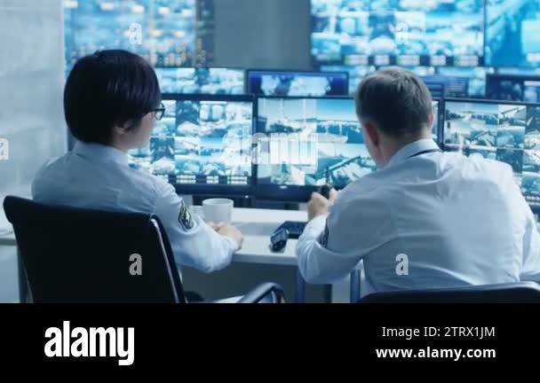 In the Security Control Room Two Officers Monitoring Multiple Screens ...