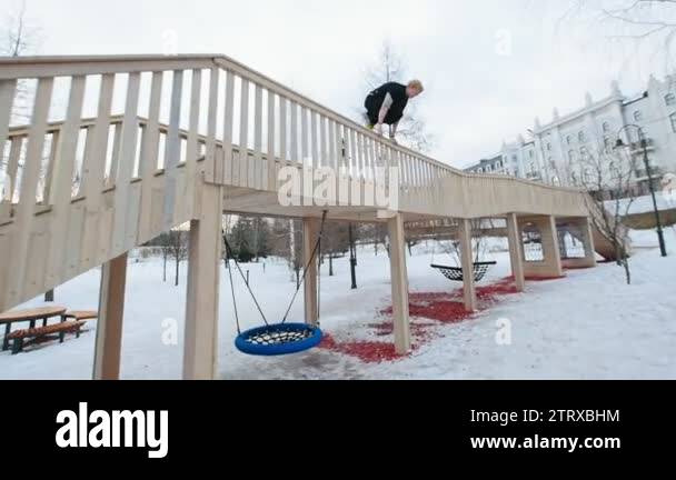 Acrobatic parkour - a free runner jumps at winter snow park, slow ...