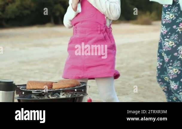 Mother and daughter fry meat and vegetables on a barbecue on the beach ...