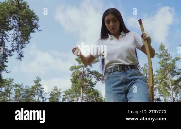 Girl preparing her bamboo long bow for shooting. Woman archer pulling ...