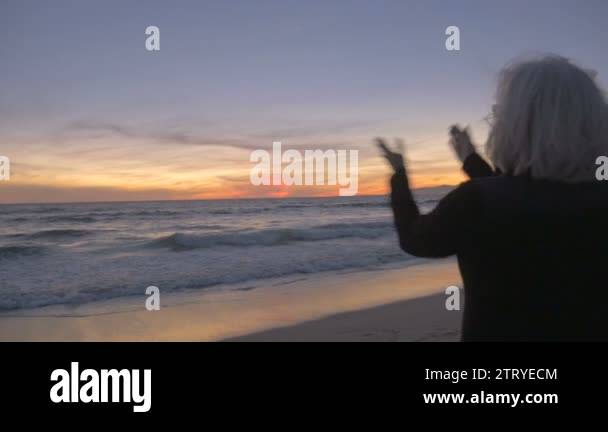 Excited happy retired fit active 60s woman clapping and enjoying sunset ...