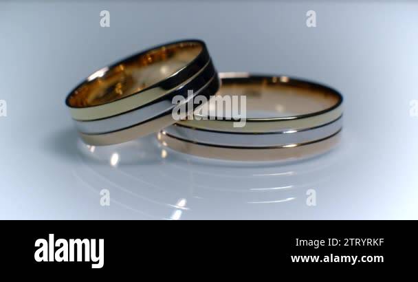 Two gold wedding rings lying on white-gray surface shining with light ...