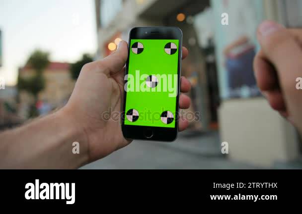 Close up man holding black smart phone with green screen in showcase background. Scrolling ...