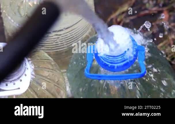 filling plastic bottles with clean drinking water from a rubber hose ...