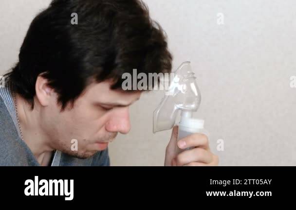 Use nebulizer and inhaler for the treatment. Young man inhaling through ...