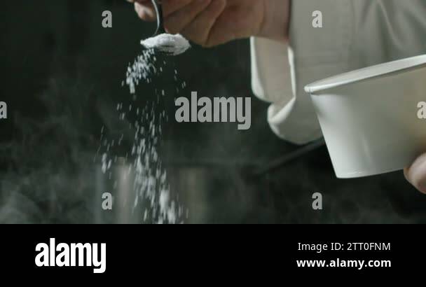 in an Italian professional kitchen a chef pours salt on a dish or in ...