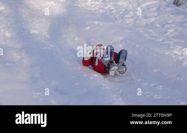 happy child slides on snow slide on sled and waves his hand. little ...