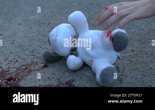 Shocked mother hugging bloody toy of dead child at car accident crime ...