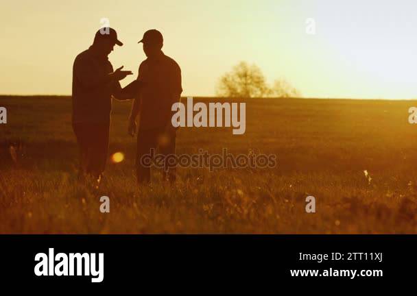 Two businessman farmers shake hands with each other firmly. They talk ...