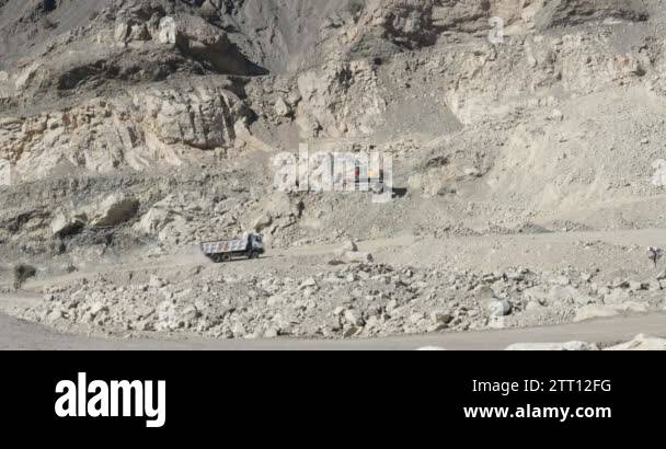 Working mine. Big white truck and shovel working on stony white hill ...