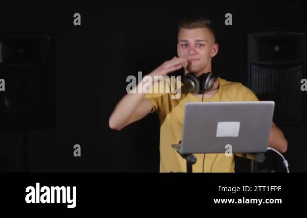 The dj mixing music standing at his deck, dance with his earphones ...