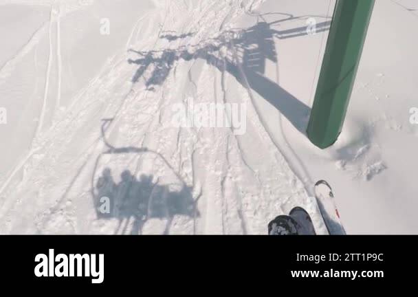 Chairlift going up snowy mountains, first person view. People with ski ...