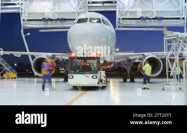 Time-Lapse of a Aircraft Maintenance Hangar Where New Airplane is Toed by a Pushback Tractor ...