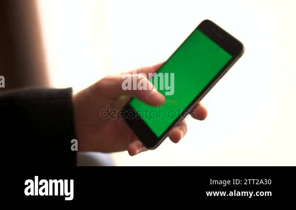 Male hand holding smart phone with green screen. Man using mobile phone ...