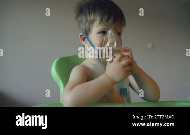 Sick child breathes through nebulizer inhalation, boy with an oxygen ...