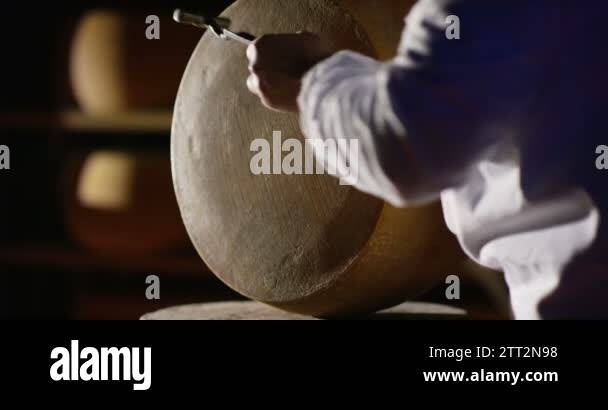Super slow motion of middle aged cheese maker cuts the wheel of Italian ...