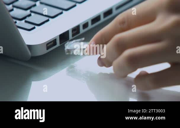 Female fingers plugging in ethernet cable into laptop port, network ...