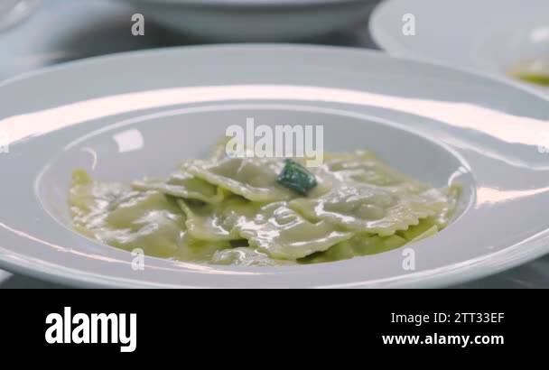 A chef decorates the freshly cooked dish consisting of Italian ravioli ...