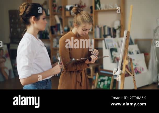 Diligent student is painting picture under guidance of professional ...