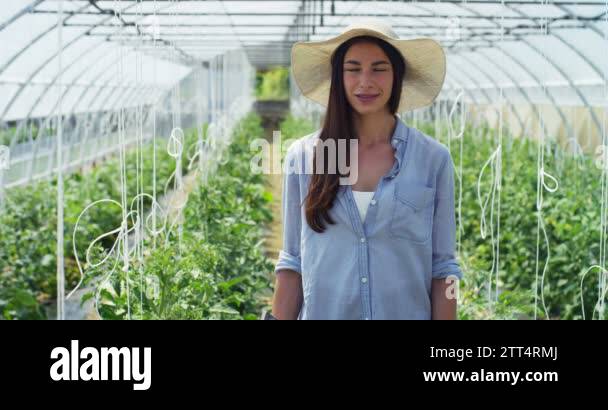 A beautiful girl in a straw hat and wearing rubber pink gloves, working ...