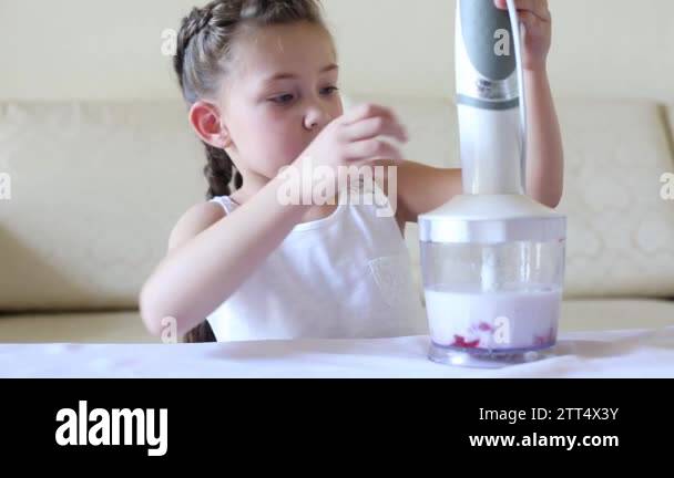 The child prepares a cocktail in a blender.A little girl prepares her ...