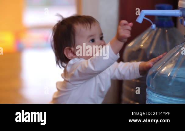 child baby girl sitting with big bottle of drinking water in diaper and ...