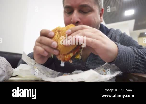 Hungry man eating big hamburger in fast food cafe Stock Video Footage ...