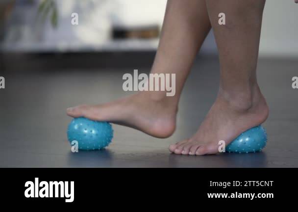 Female rolling feet on massaging ball, stretching bottom of foot, pain ...
