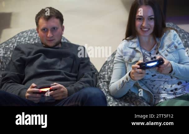 Young couple playing video game at home. Shooting and controlling using ...