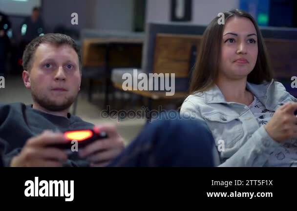 Young couple playing video game at home. Man explayning how to play and ...