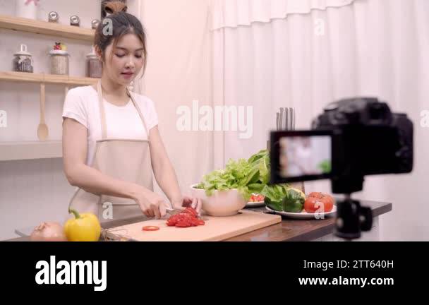 Blogger Asian woman using camera recording how to make salad healthy food video for her ...