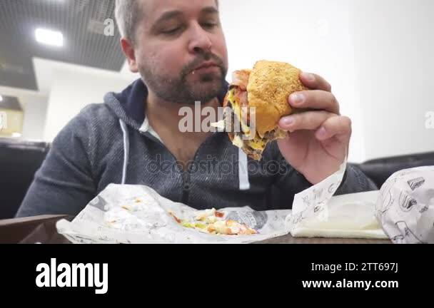 Hungry man eating big hamburger in fast food cafe Stock Video Footage ...
