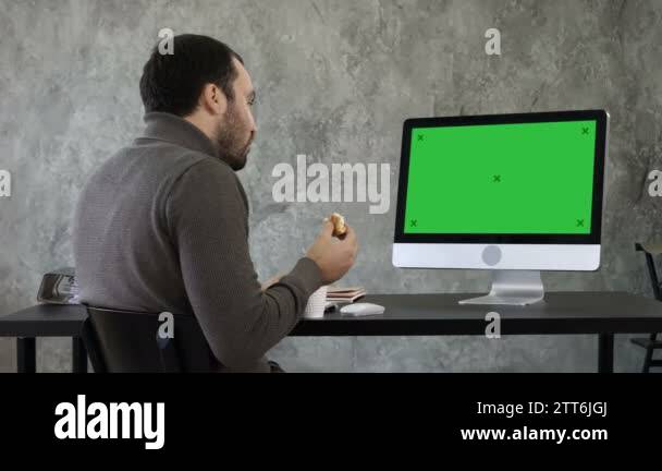 Young man choking while eating and watching something on the computer ...