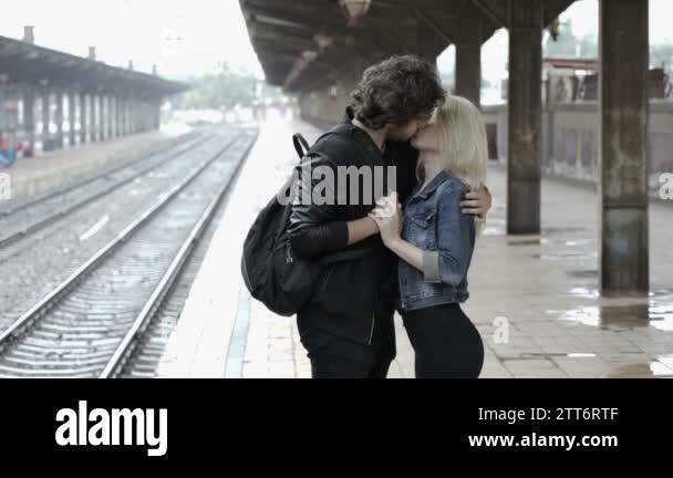 Romantic couple kissing and hugging in train station on rainy day ...