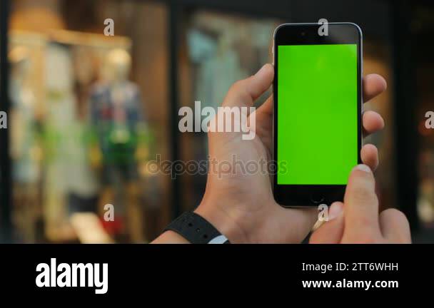 Man holding black smart phone with green screen in showcase background. Scrolling, tapping ...