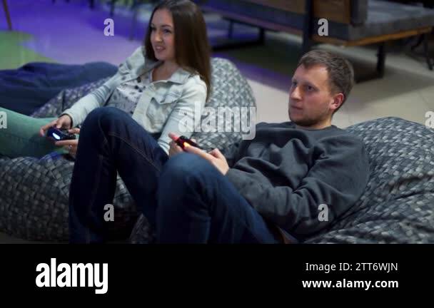 Young couple playing video game at home. Shooting and controlling using ...