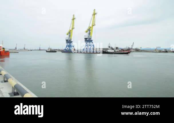 Towing cranes for containers timelapse. Tugboat assisting container vessel to departure after ...