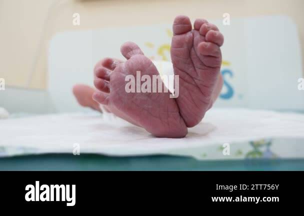 Newborn baby girl lying on back. Baby is kicking and stretching legs ...